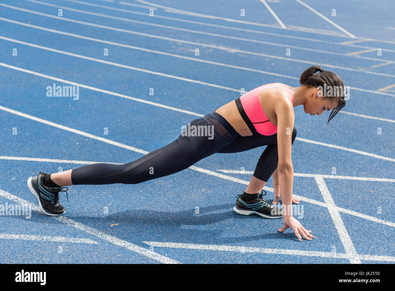 Side view of athletic young woman in sportswear on starting line ready ...