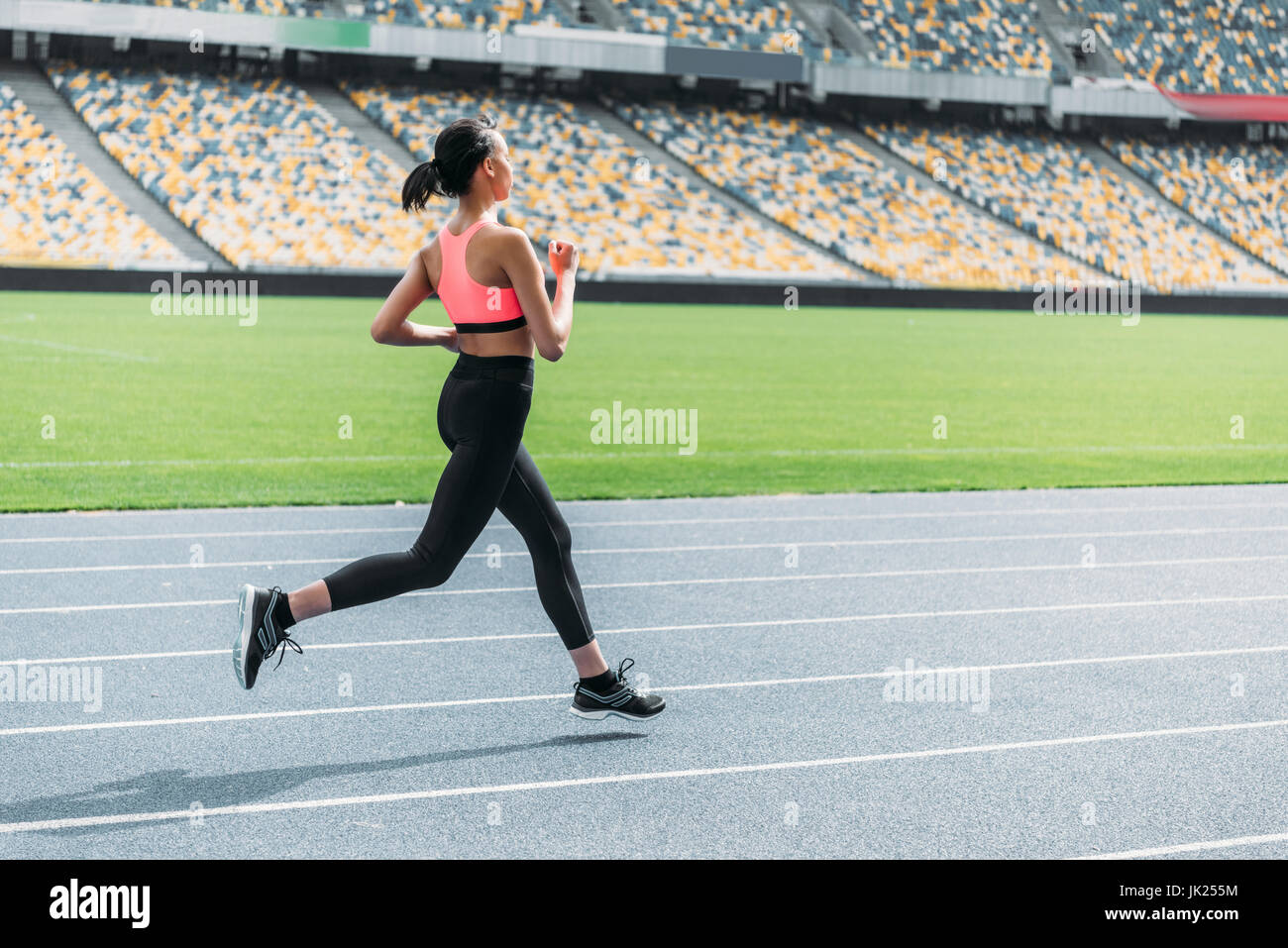 Side view of athletic young woman in sportswear sprinting on running ...
