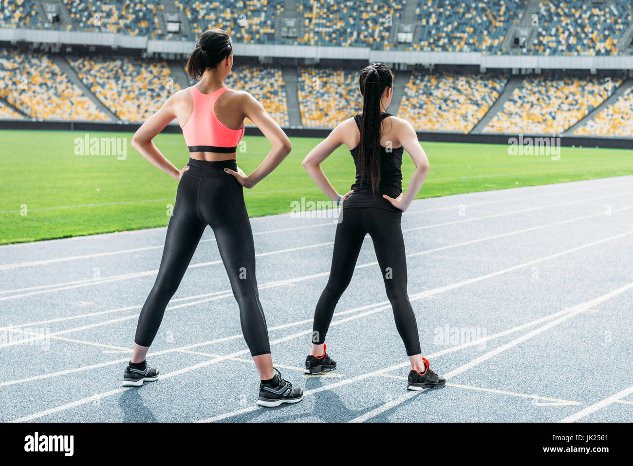 Athletic young women in sportswear exercising on running track stadium ...