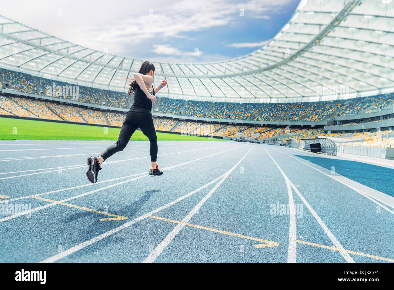 Young fitness woman in sportswear running on running track stadium ...