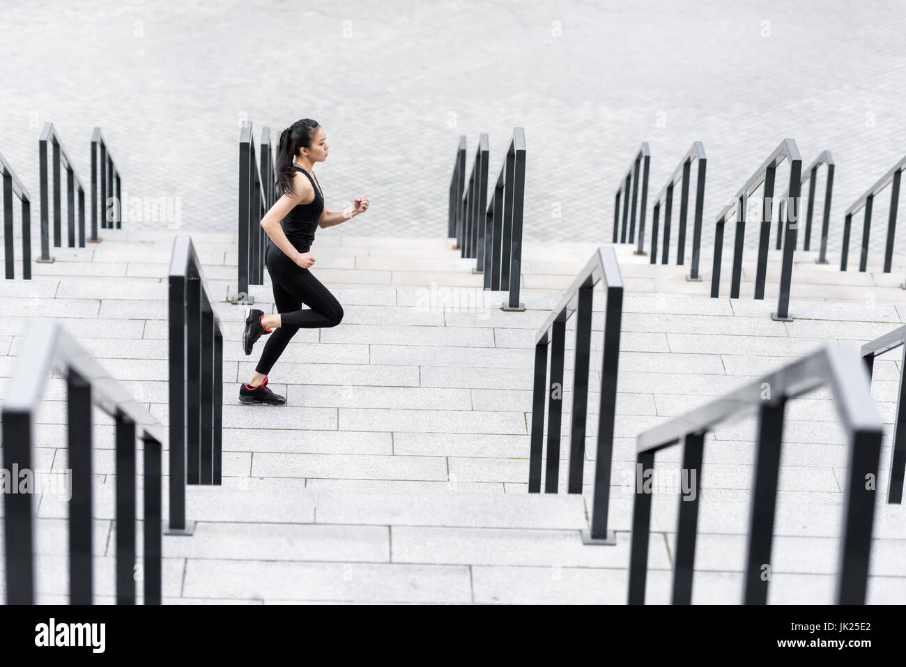 Side view of athletic young woman in sportswear running on stadium ...
