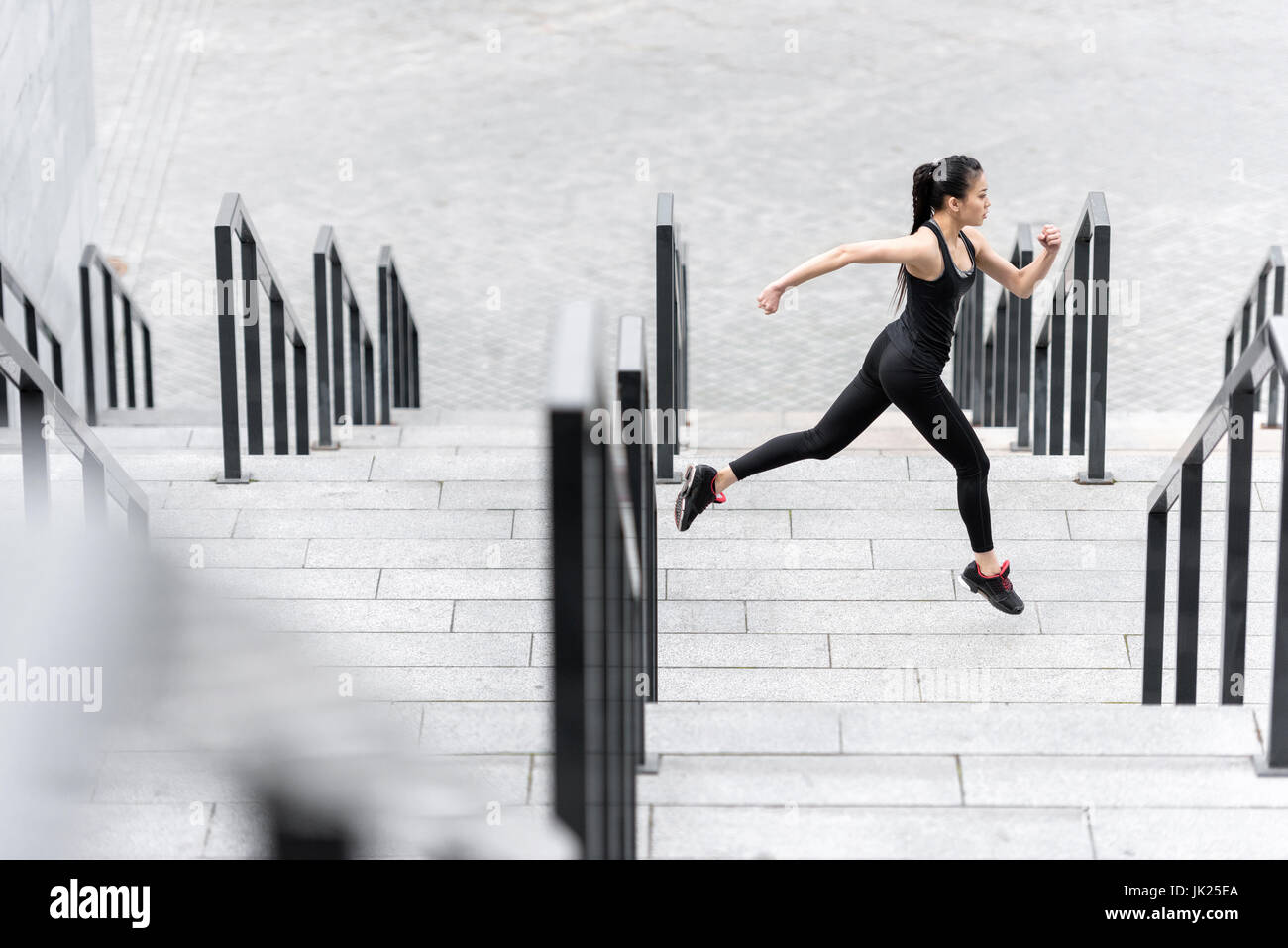 Side view of athletic young woman in sportswear running on stadium ...