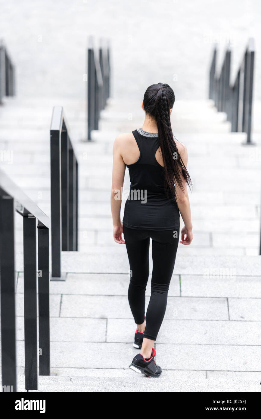Back view of athletic young woman in sportswear walking on stadium ...