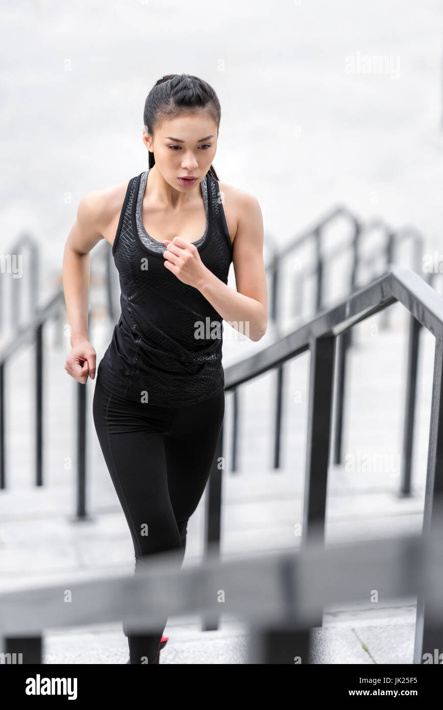 Young asian woman in sportswear running up on stadium stairs Stock ...