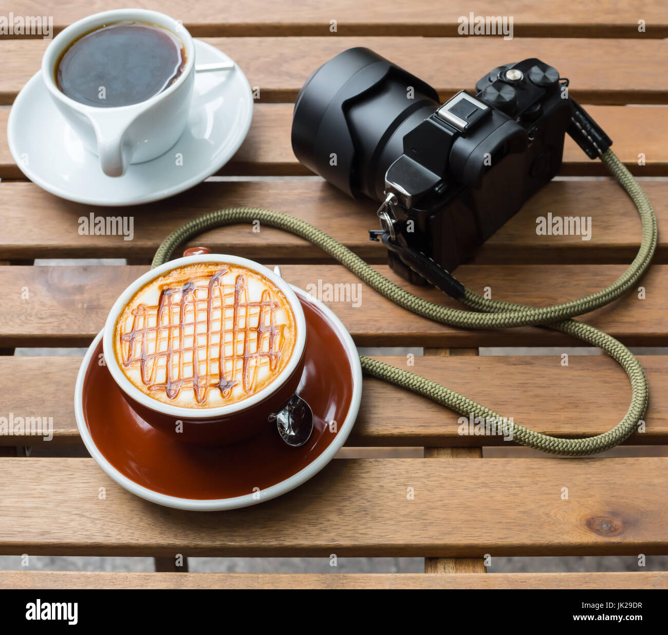 two coffee cups and a camera on a wood table Stock Photo - Alamy