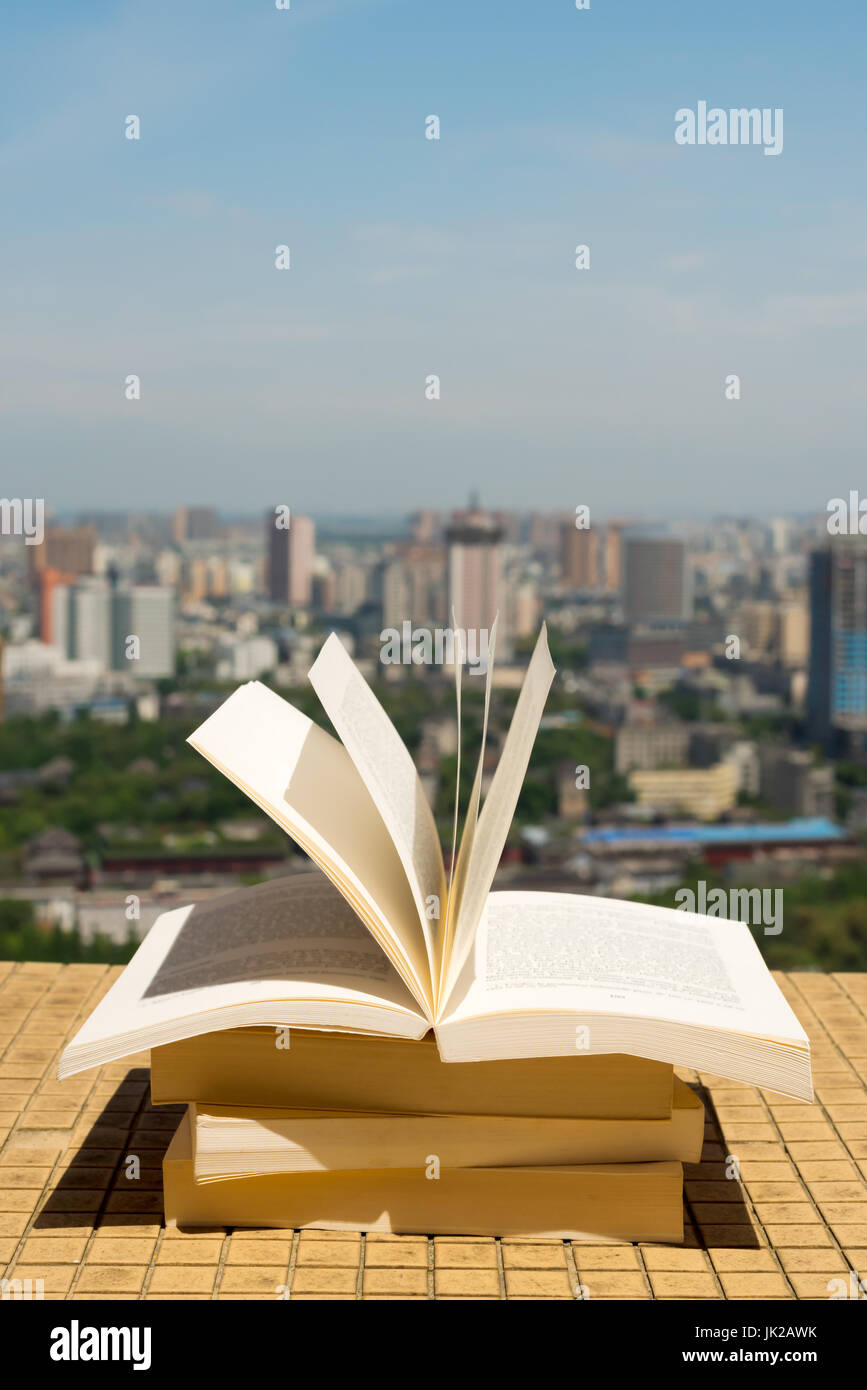 Books stack on a roof with the city in the background Stock Photo - Alamy
