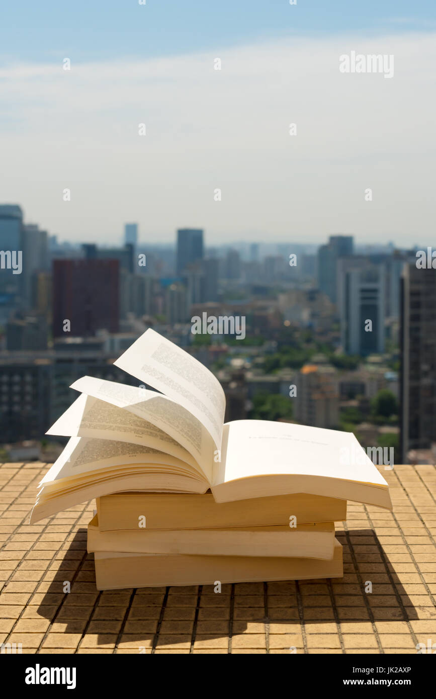 Books stack on a roof with the city in the background Stock Photo - Alamy