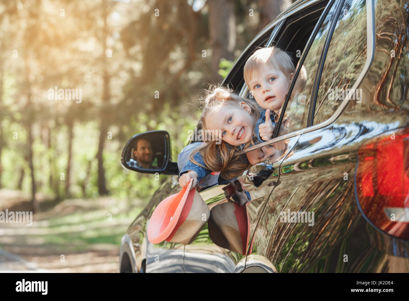 Travel by car family ride together brother and sister lean out of the ...