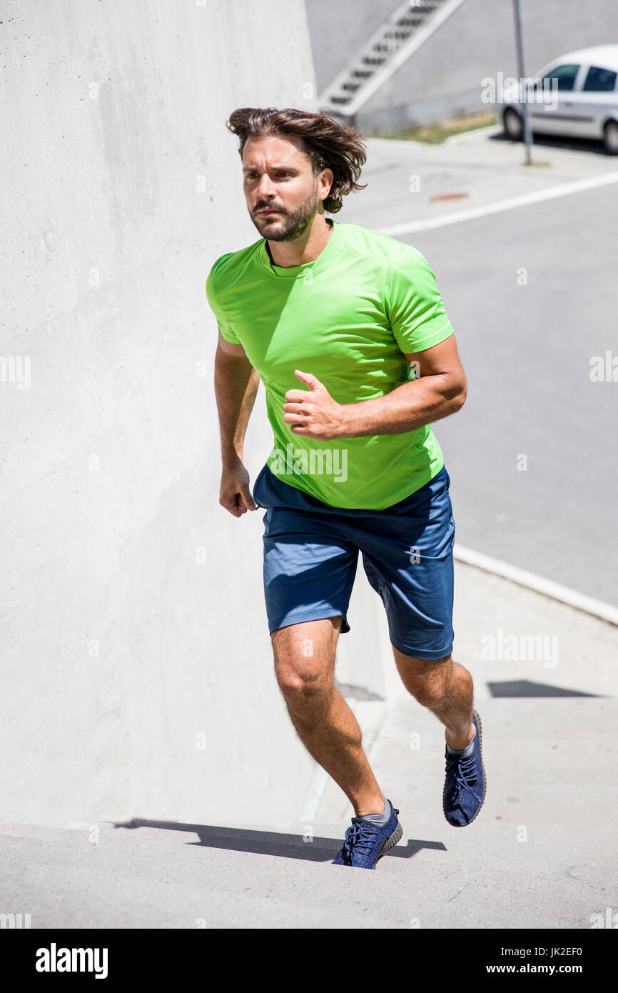 Young man running on the street in urban environment at sunny day Stock ...