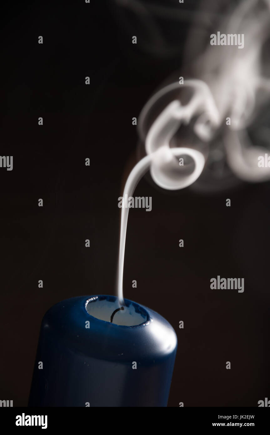 White smoke rising from an extinguished candle against a black ...