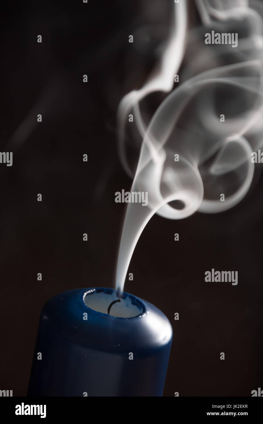 White smoke rising from an extinguished candle against a black ...
