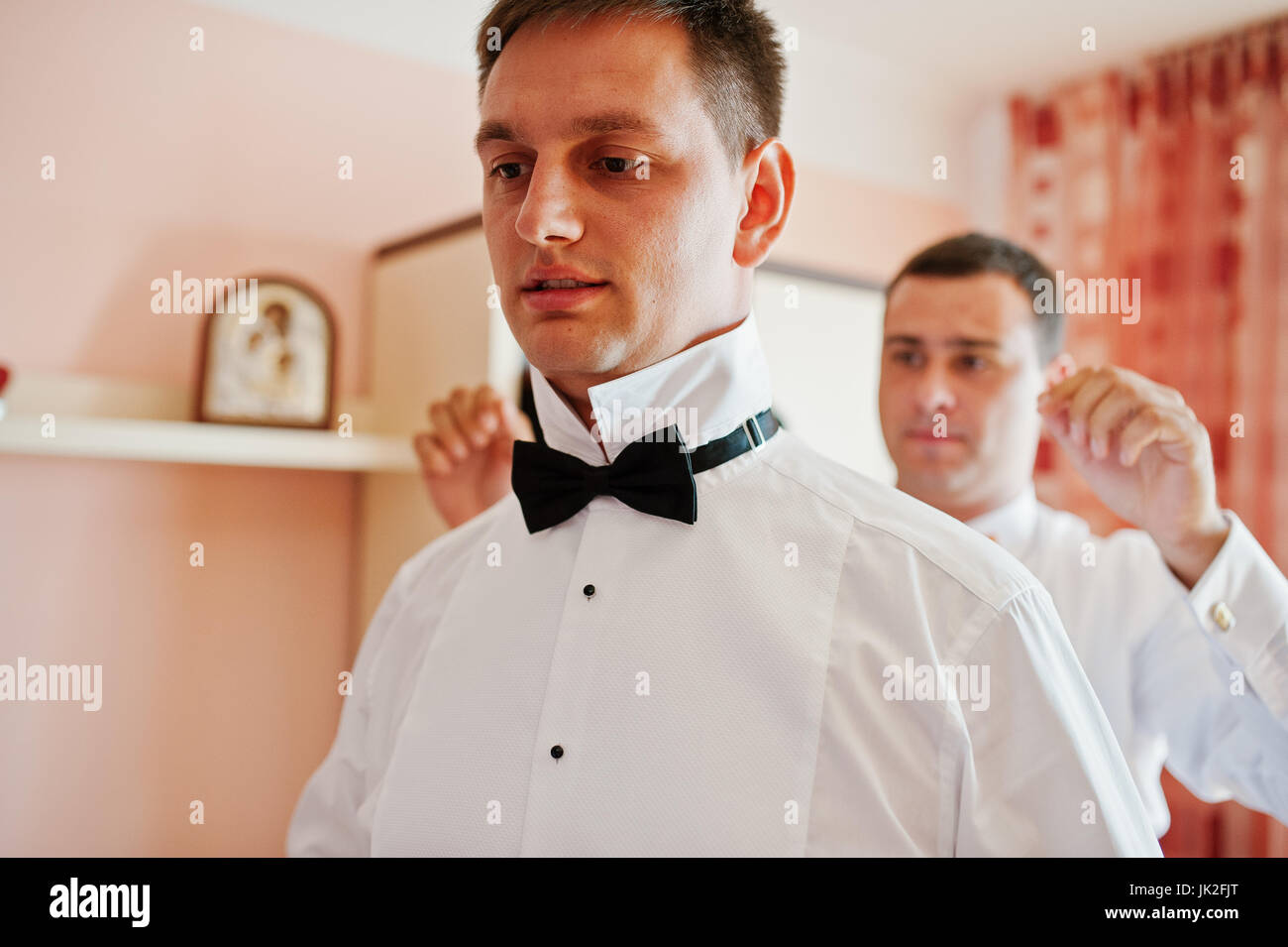 Helpful groomsmen or bestmen helping groom to get ready for his wedding ...