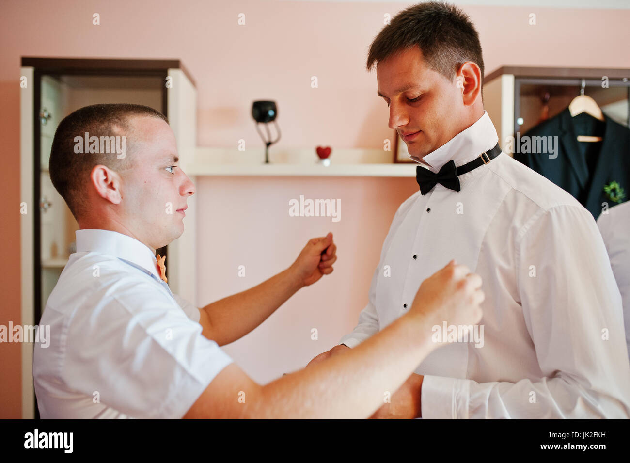 Helpful groomsmen or bestmen helping groom to get ready for his wedding ...