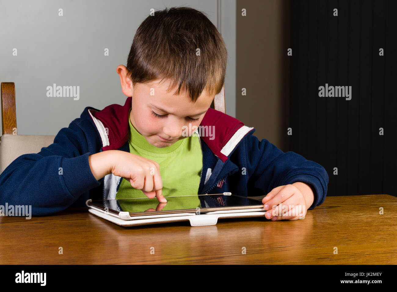 Little boy playing on a tablet computer at the living room table Stock ...