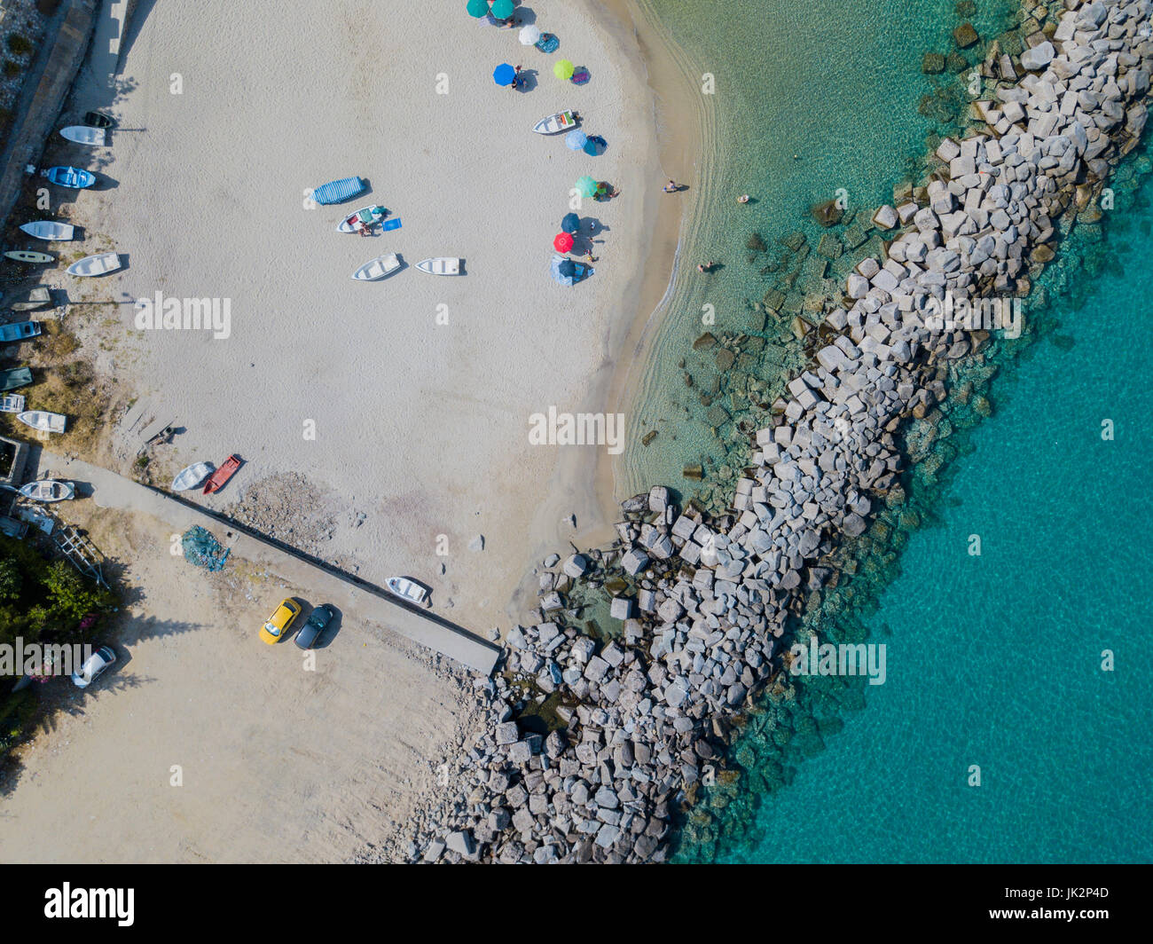 Aerial view of a beach and a pier with canoes, boats and umbrellas ...