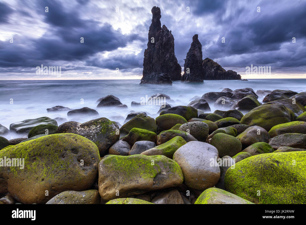 Seascape with giant rocks in the ocean at dawn and green stones beach ...