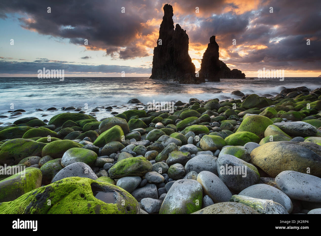 Seascape with giant rocks in the ocean at dawn and green stones beach ...
