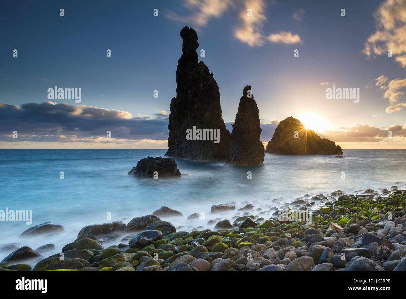 Seascape with giant rocks in the ocean at sunrise and green stones ...