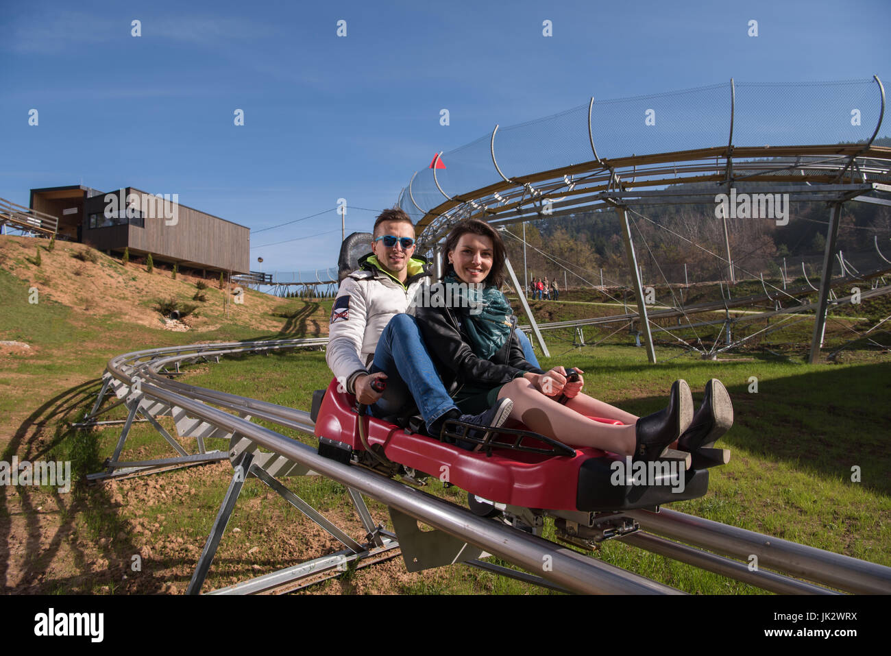 Excited young couple enjoys driving on alpine coaster Stock Photo - Alamy