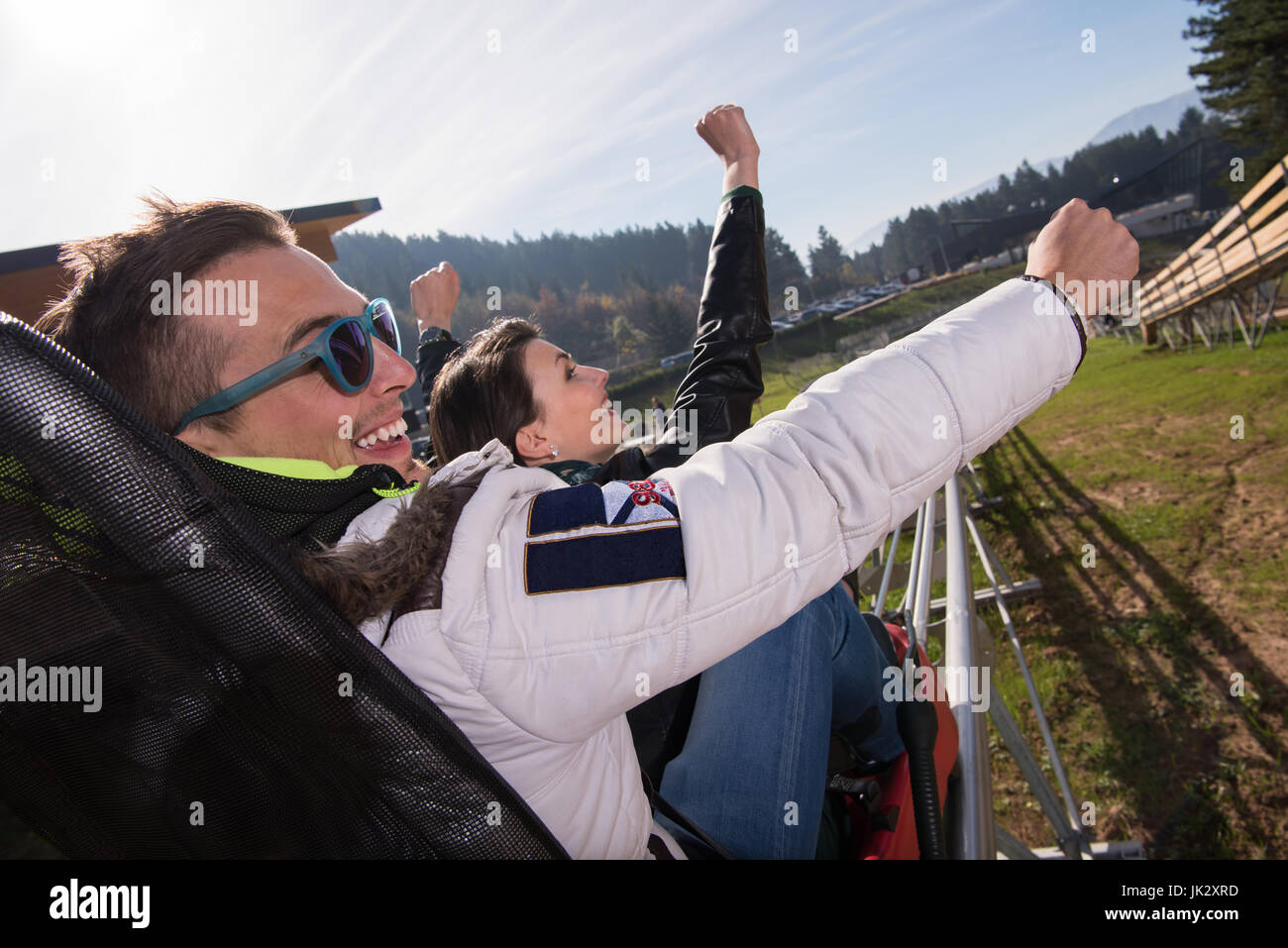 Excited young couple enjoys driving on alpine coaster Stock Photo - Alamy