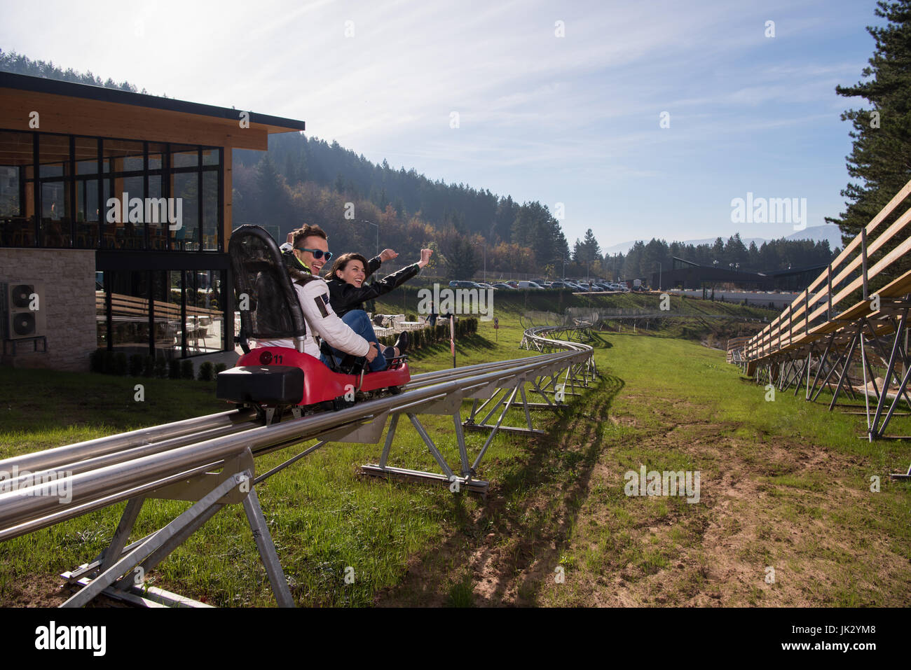 Excited young couple enjoys driving on alpine coaster Stock Photo - Alamy