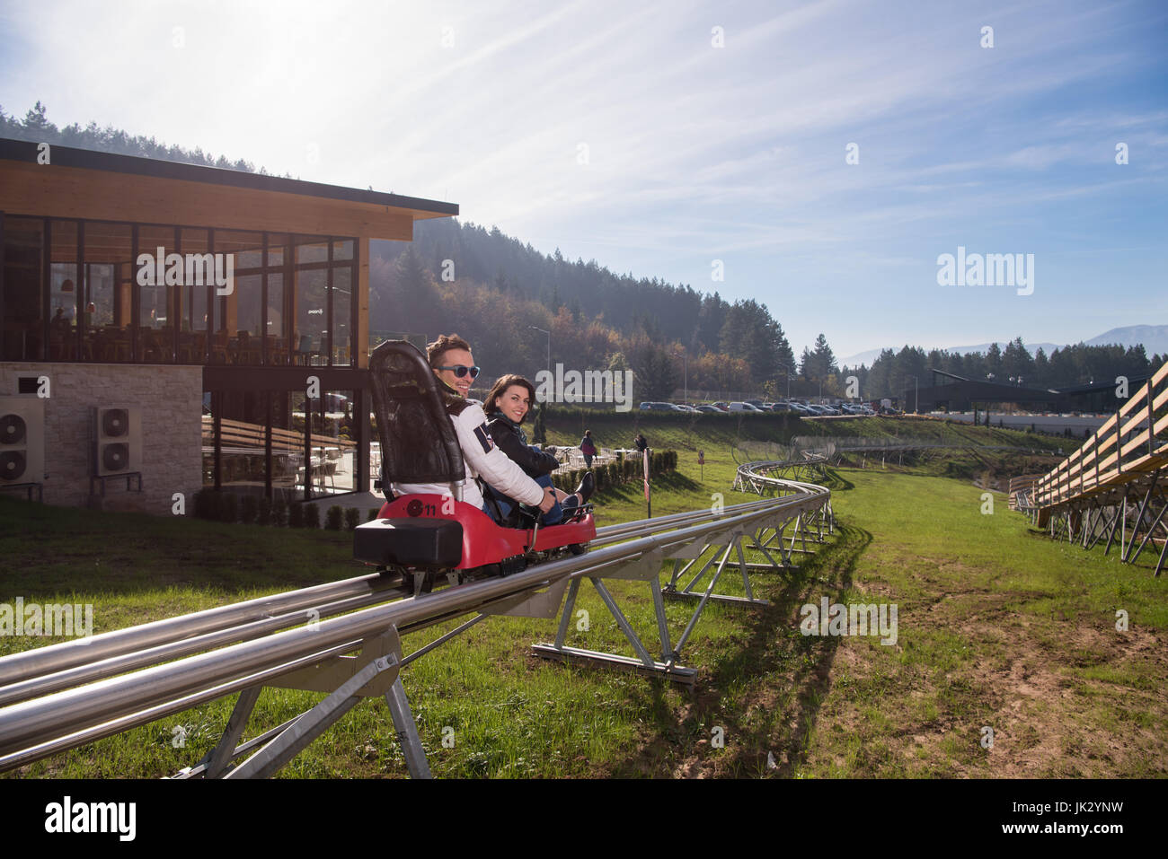 Excited young couple enjoys driving on alpine coaster Stock Photo - Alamy