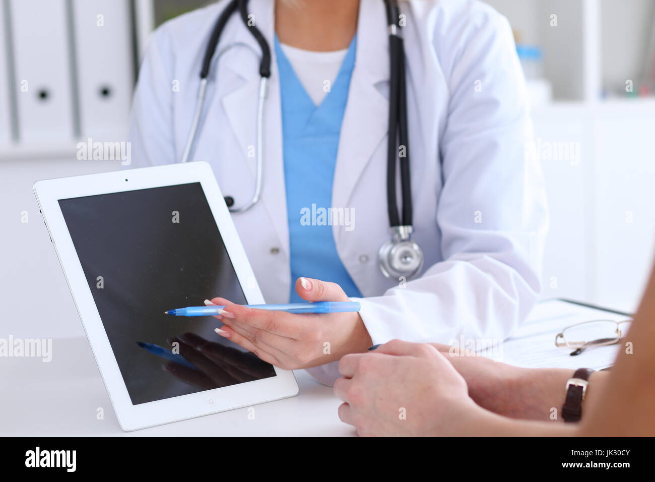 Close up of a doctor and patient hands while phisician pointing into ...
