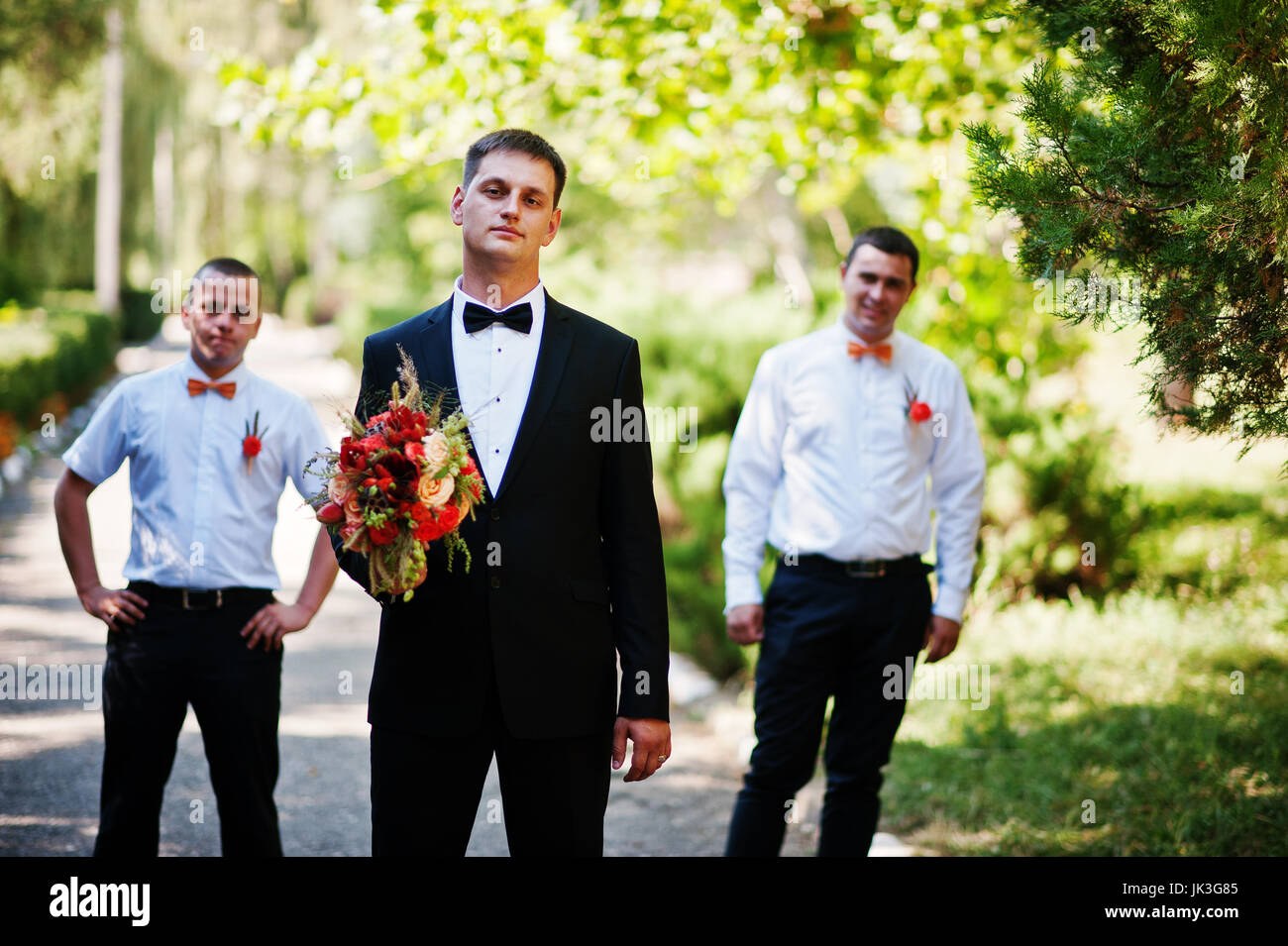 Handsome groom walking with his bestmen or groomsmen in the park on a ...