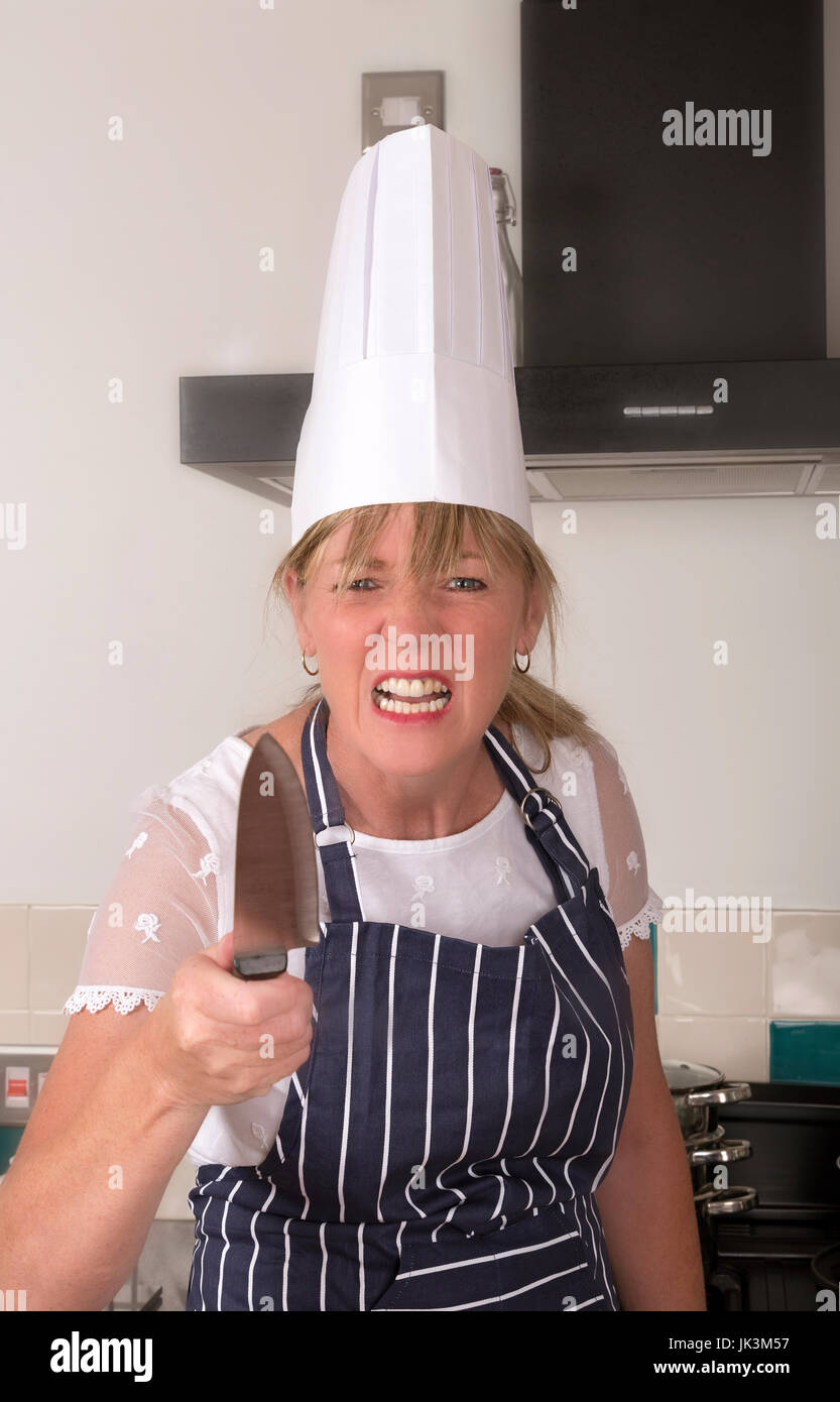 Portrait of a very angry chef holding a sharp kitchen knife in a ...