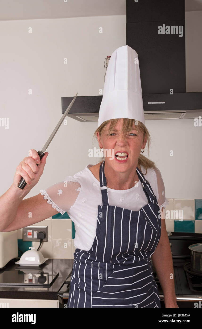 Portrait of a very angry chef holding a sharp kitchen knife in a ...
