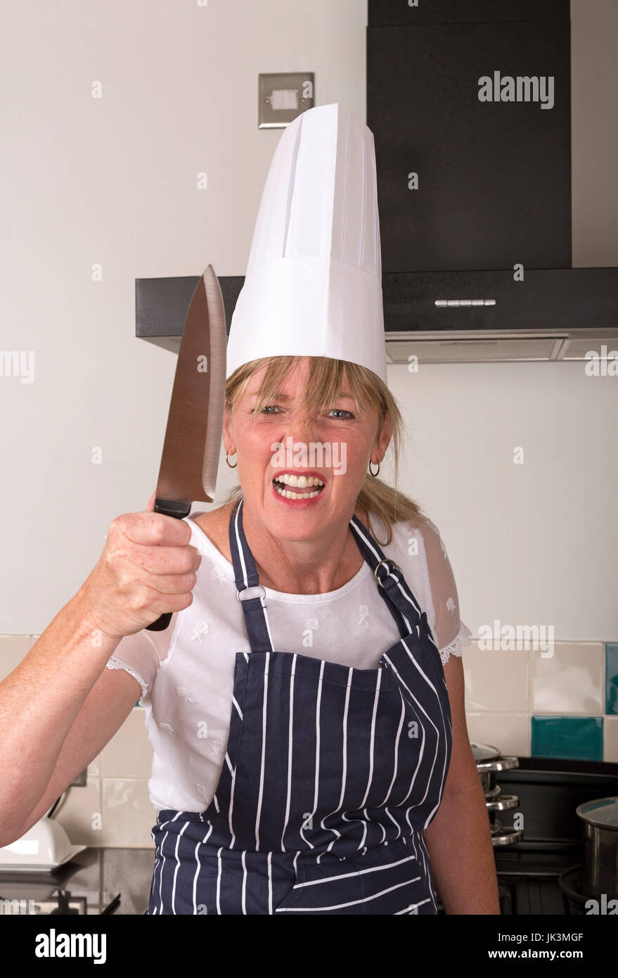 Portrait of a very angry chef holding a sharp kitchen knife in a ...