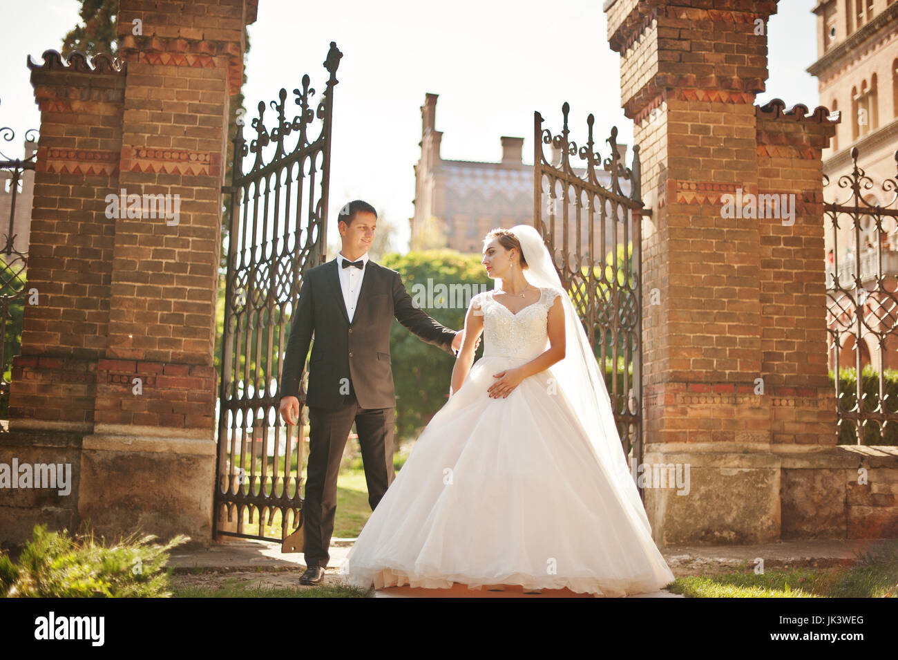 Newly married couple posing next to the gates on their wedding day ...