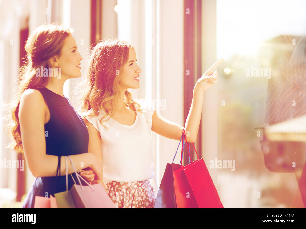 happy women with shopping bags at shop window Stock Photo - Alamy