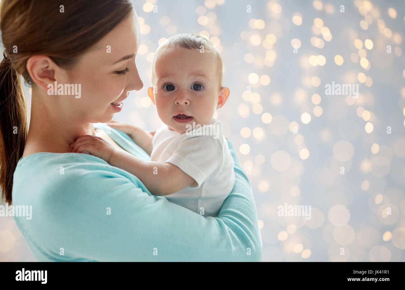 happy young mother with little baby over lights Stock Photo - Alamy