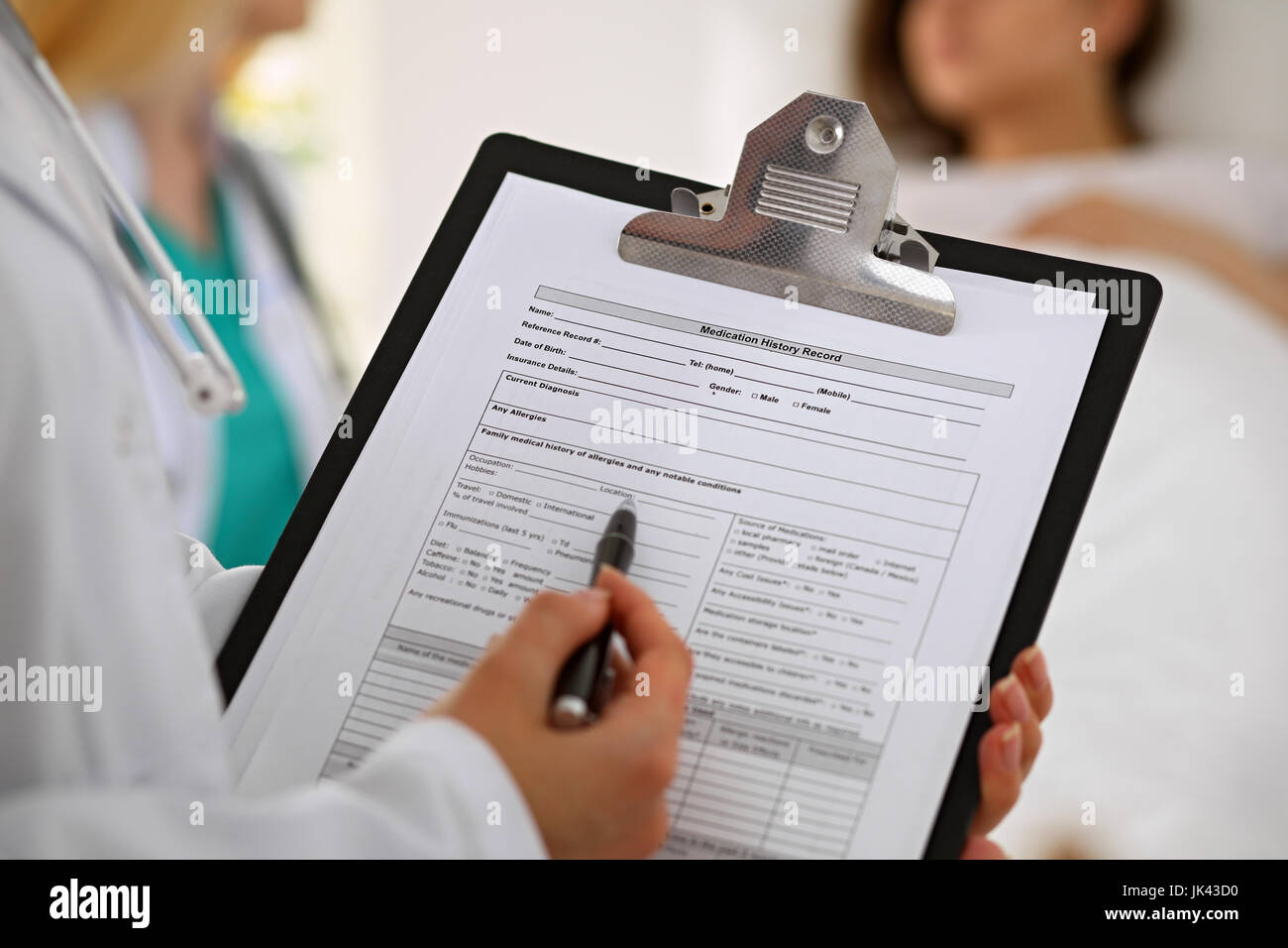 Close-up of a female doctor while filling up medical history record ...