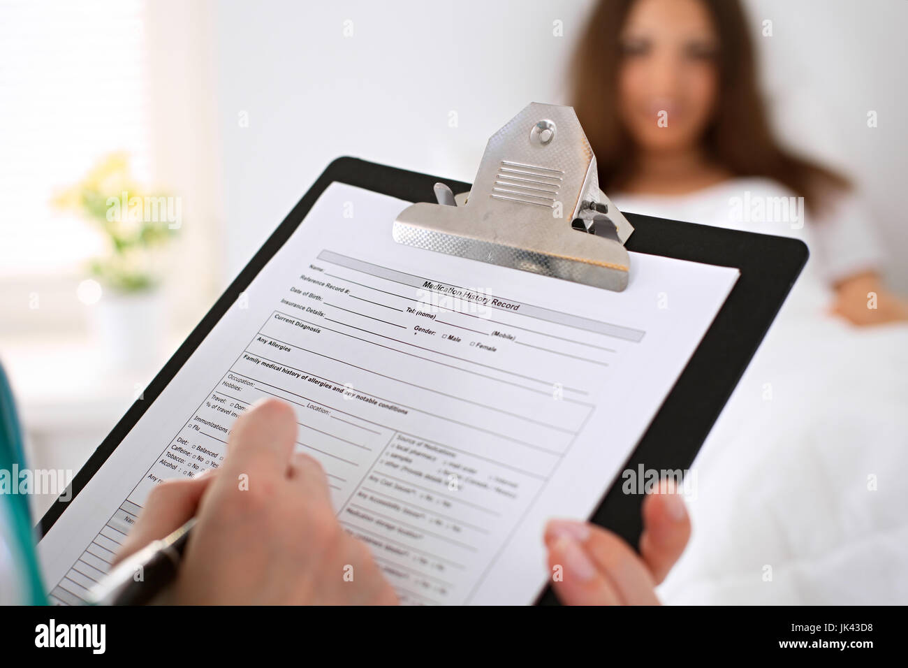 Close-up of a female doctor while filling up medical history record ...