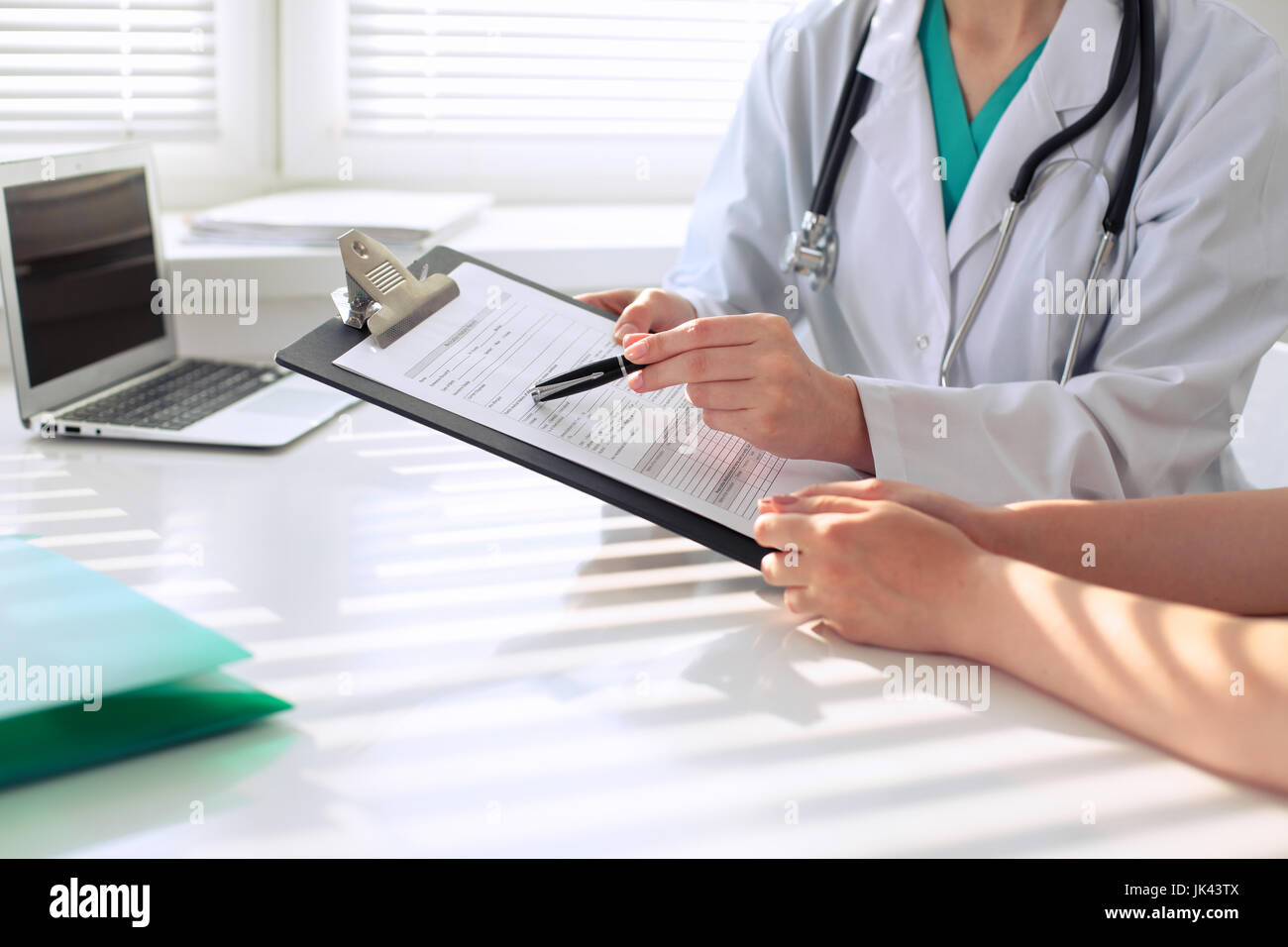 Doctor pointing into medical history form and discussing something with ...