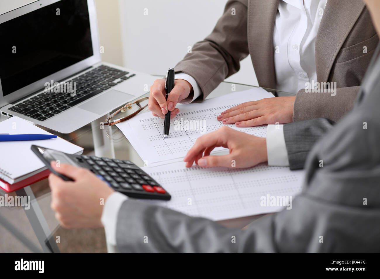 Two female accountants counting on calculator income for tax form ...