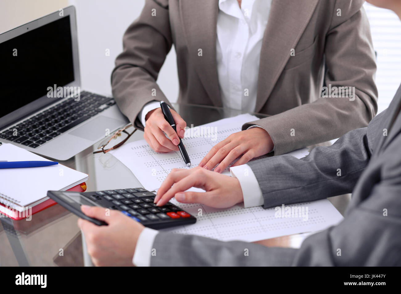 Two female accountants counting on calculator income for tax form ...