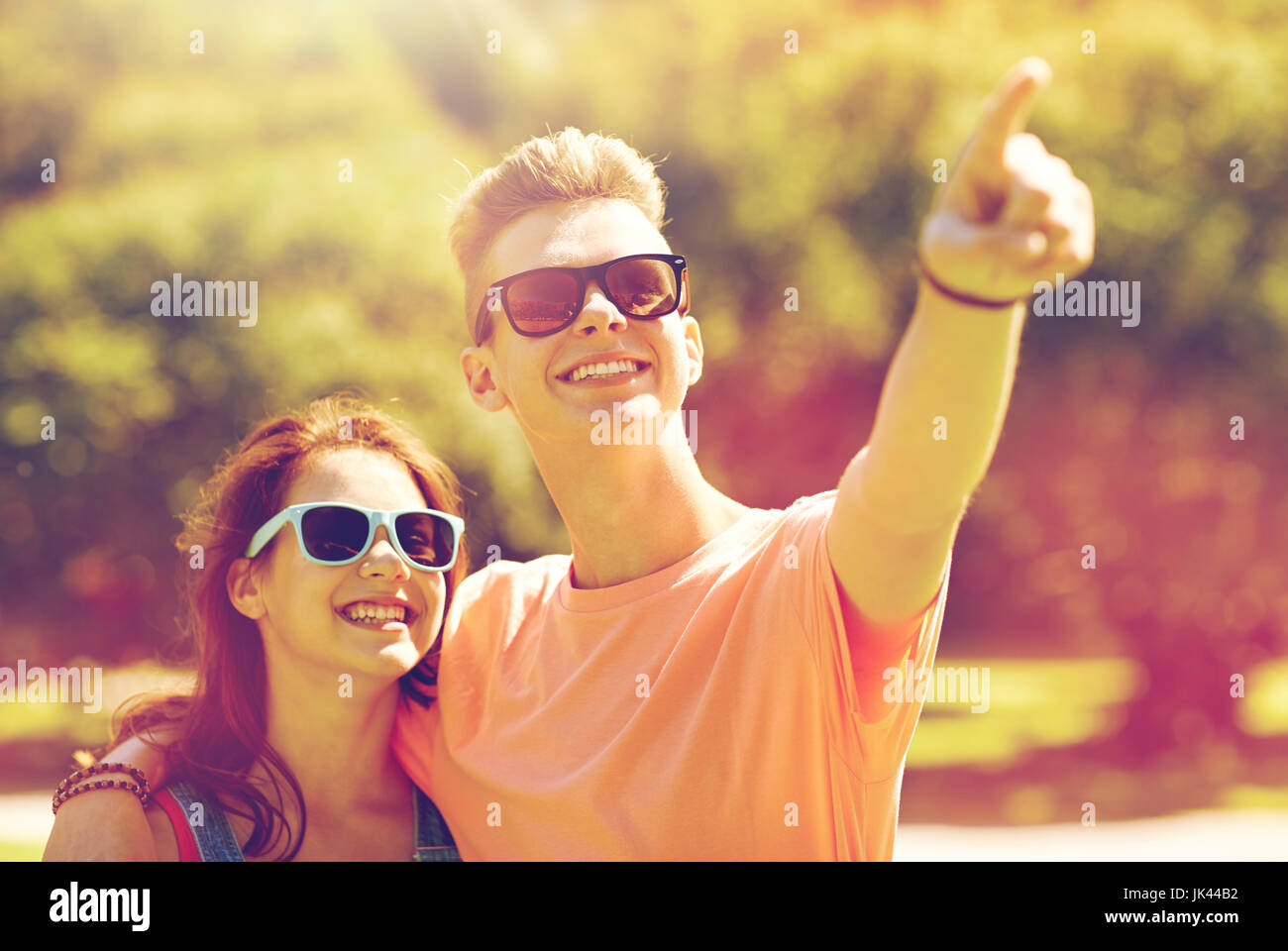 happy couple pointing finger at summer park Stock Photo - Alamy