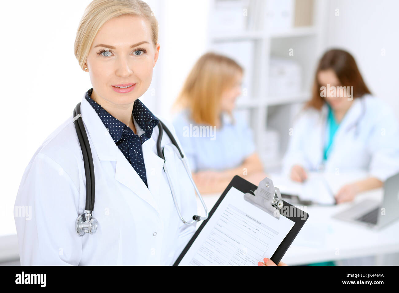 Female doctor smiling on the background with patient and his physician ...
