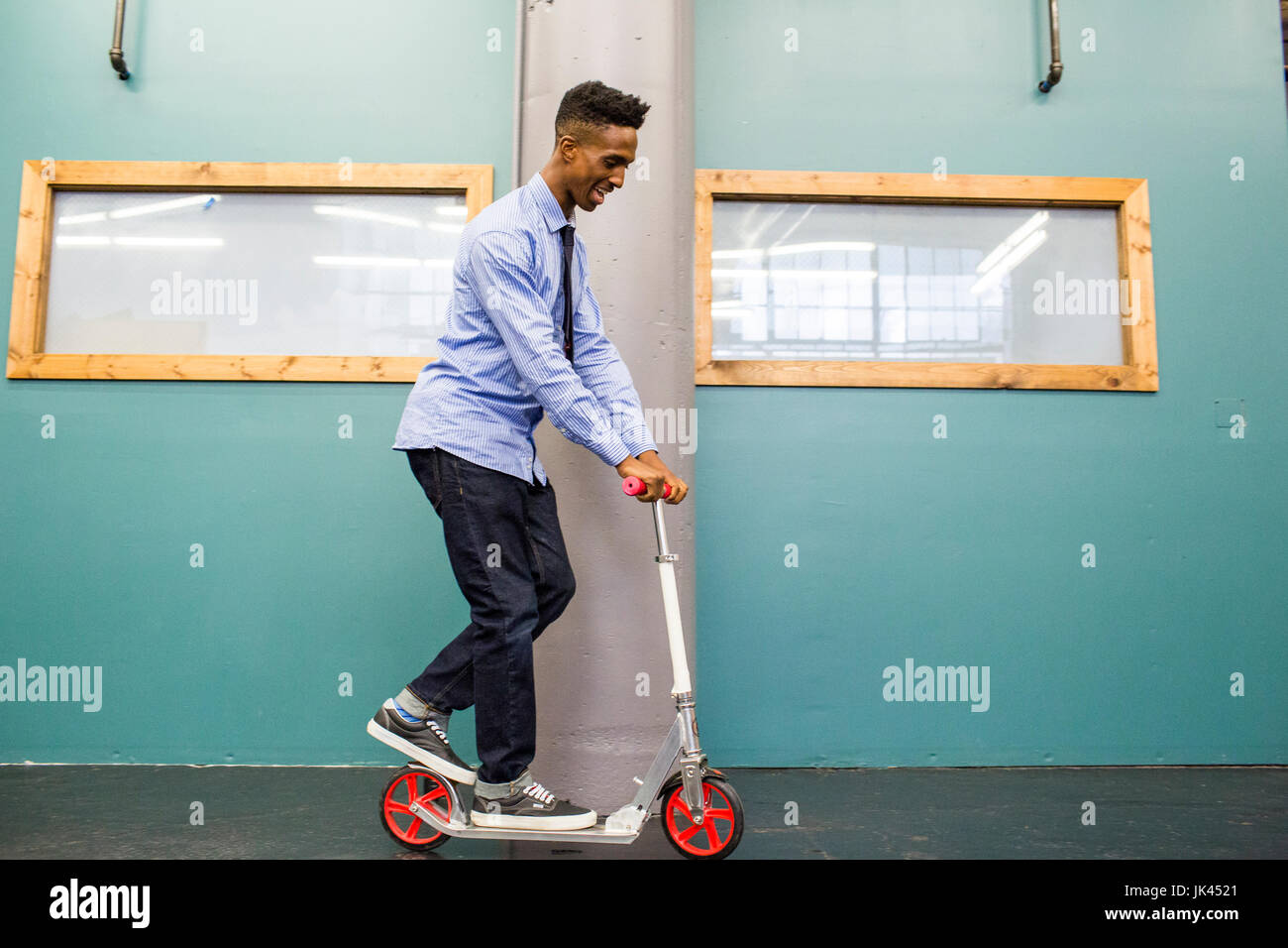 Black man riding scooter indoors Stock Photo - Alamy