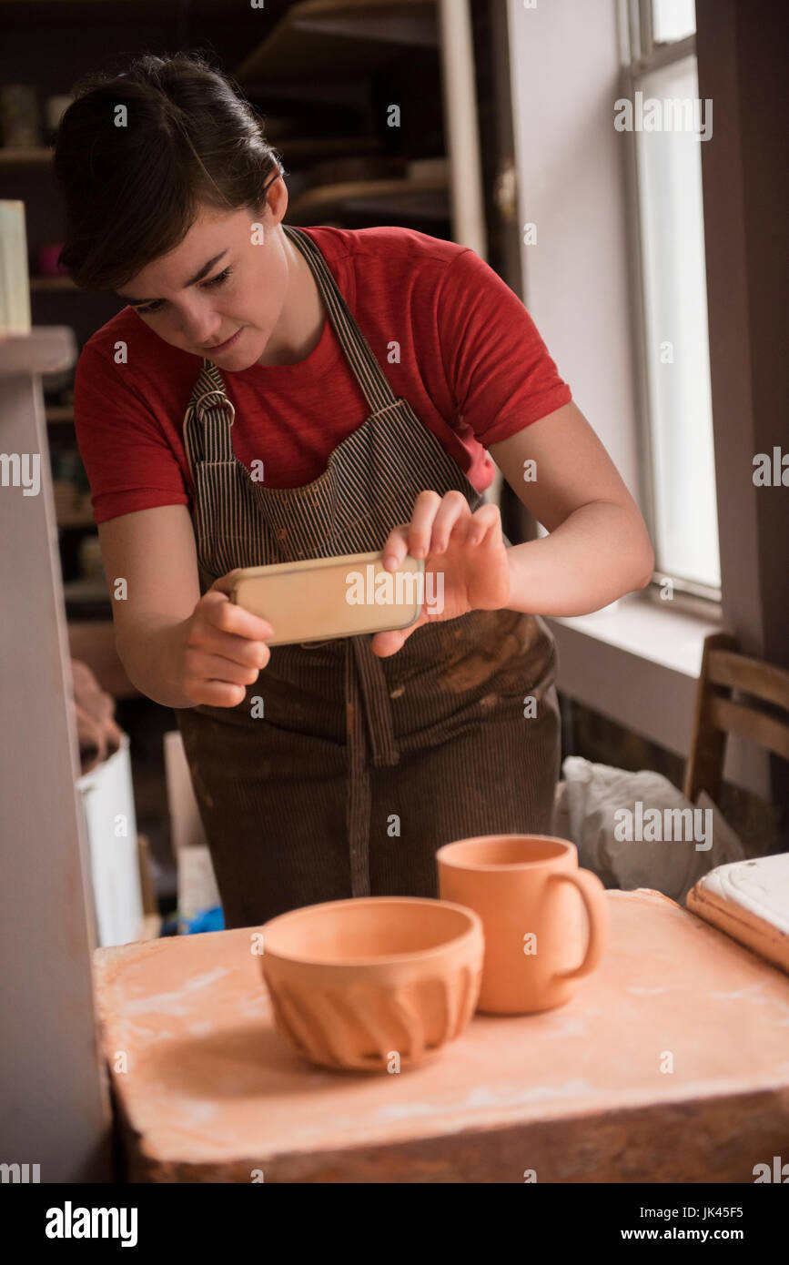 Caucasian woman photographing pottery with cell phone Stock Photo - Alamy