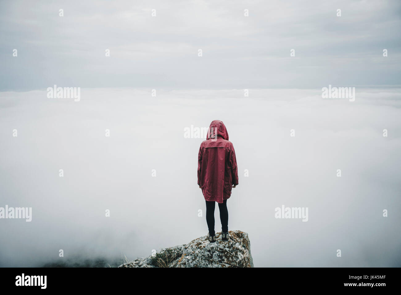 Distant Caucasian woman standing on rock watching fog on ocean Stock ...