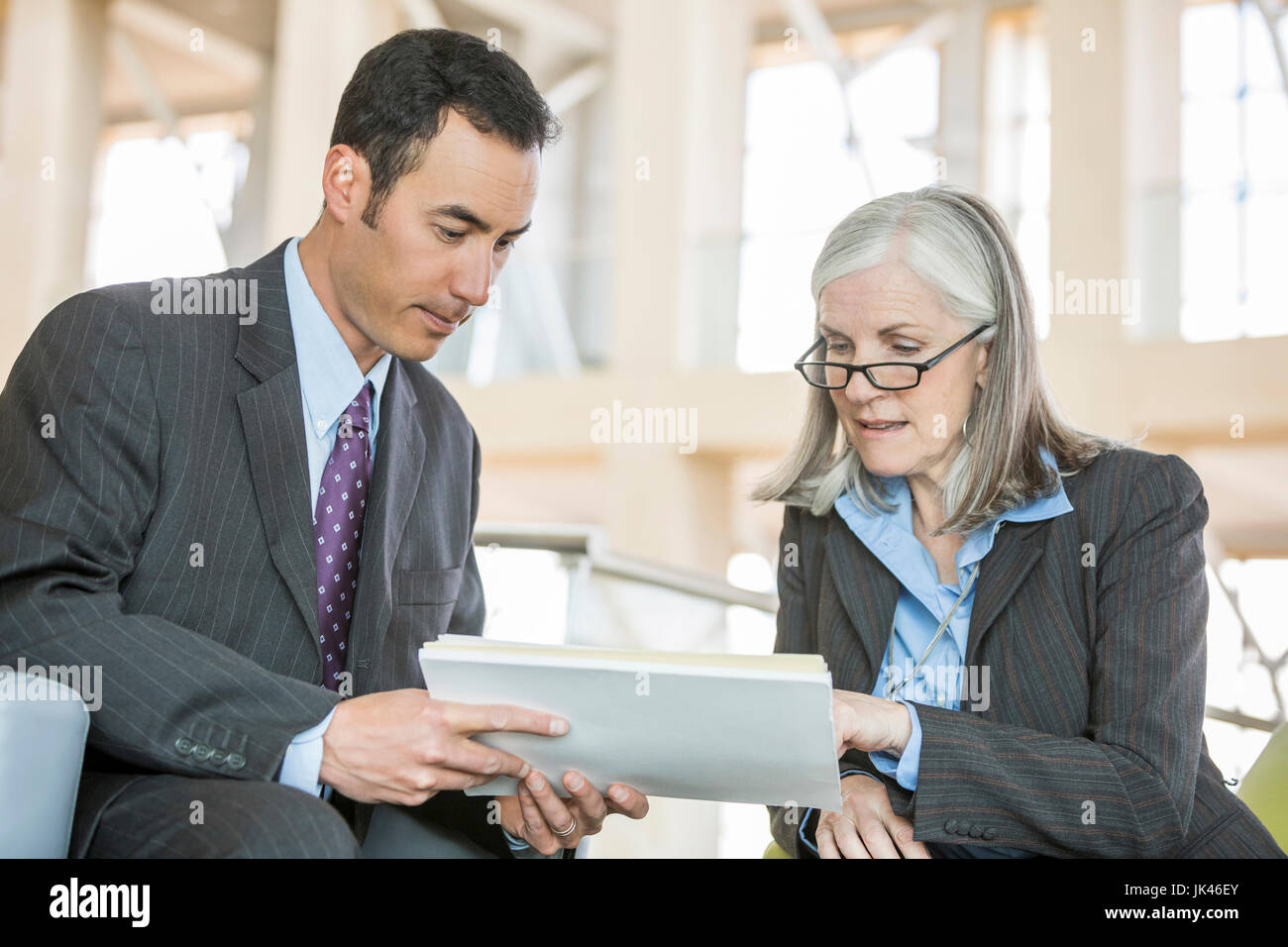 Business people reading paperwork in lobby Stock Photo - Alamy