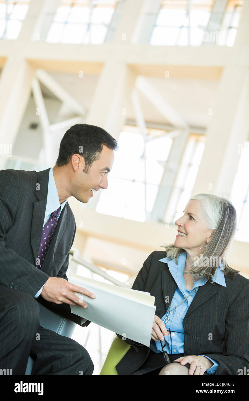Smiling business people reading paperwork in lobby Stock Photo - Alamy