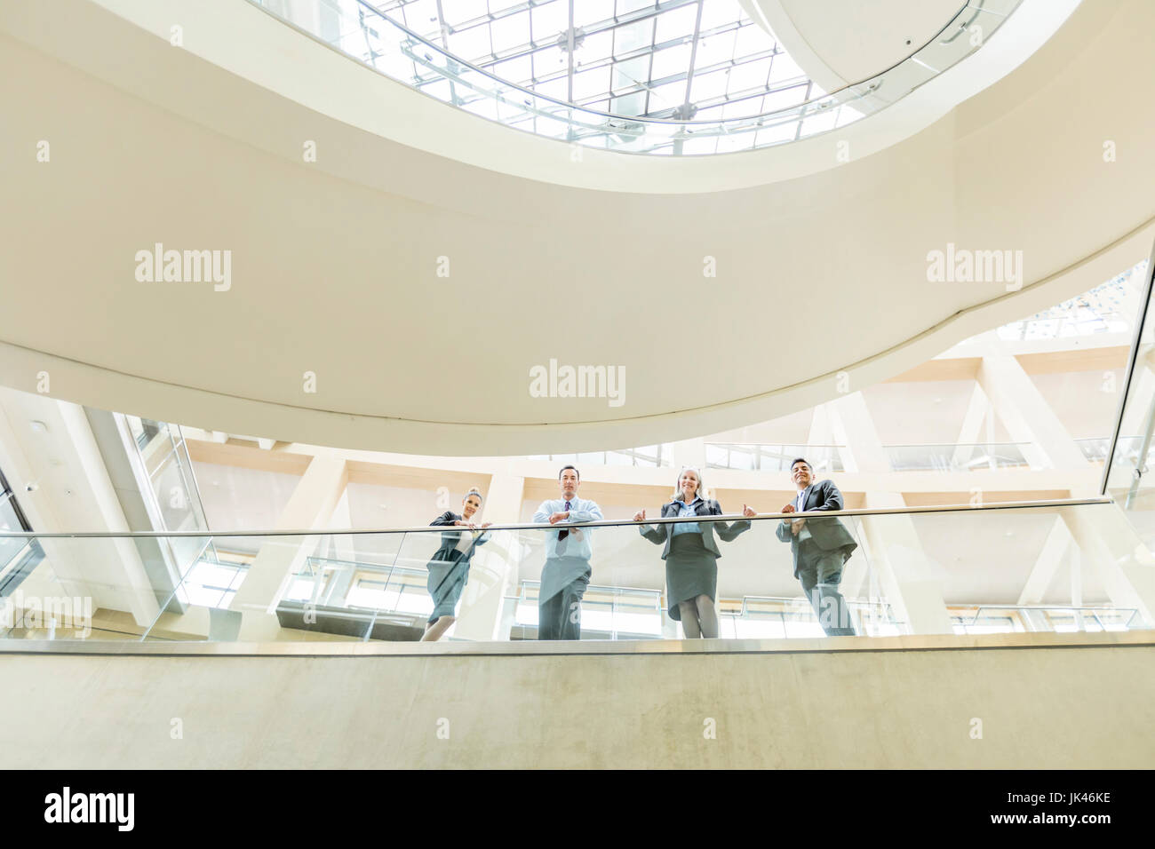 Portrait of smiling business people leaning on railing in lobby Stock ...