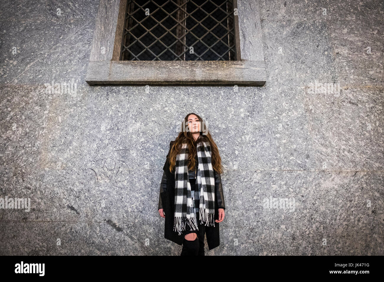 Serious Caucasian woman leaning on wall under window Stock Photo - Alamy