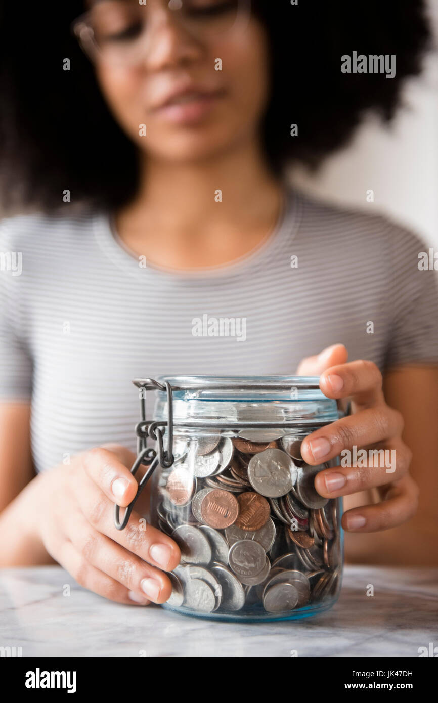 Smiling African American woman with jar full of coins Stock Photo - Alamy