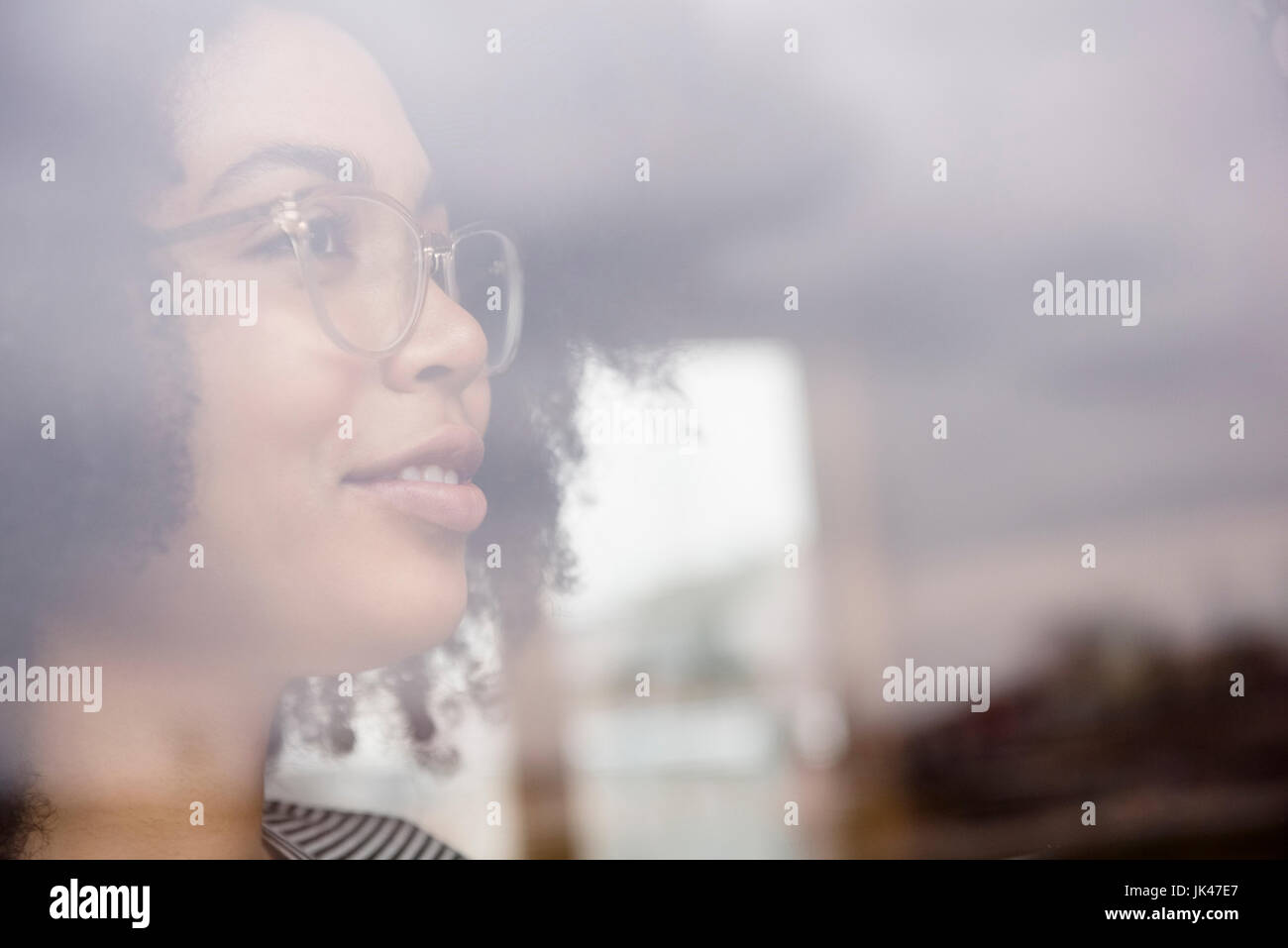 Smiling African American woman behind window Stock Photo - Alamy